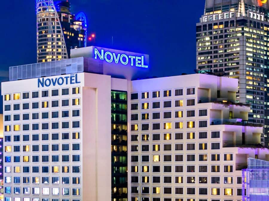 Um hotel Novotel com fachada moderna, vários andares e uma placa chamativa.