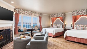 Quarto de hotel com duas camas, lareira, televisão e área de refeições com uma bandeja de café da manhã.