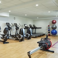 Uma academia com diversos equipamentos de ginástica, incluindo esteiras, elípticos e bicicletas ergométricas.