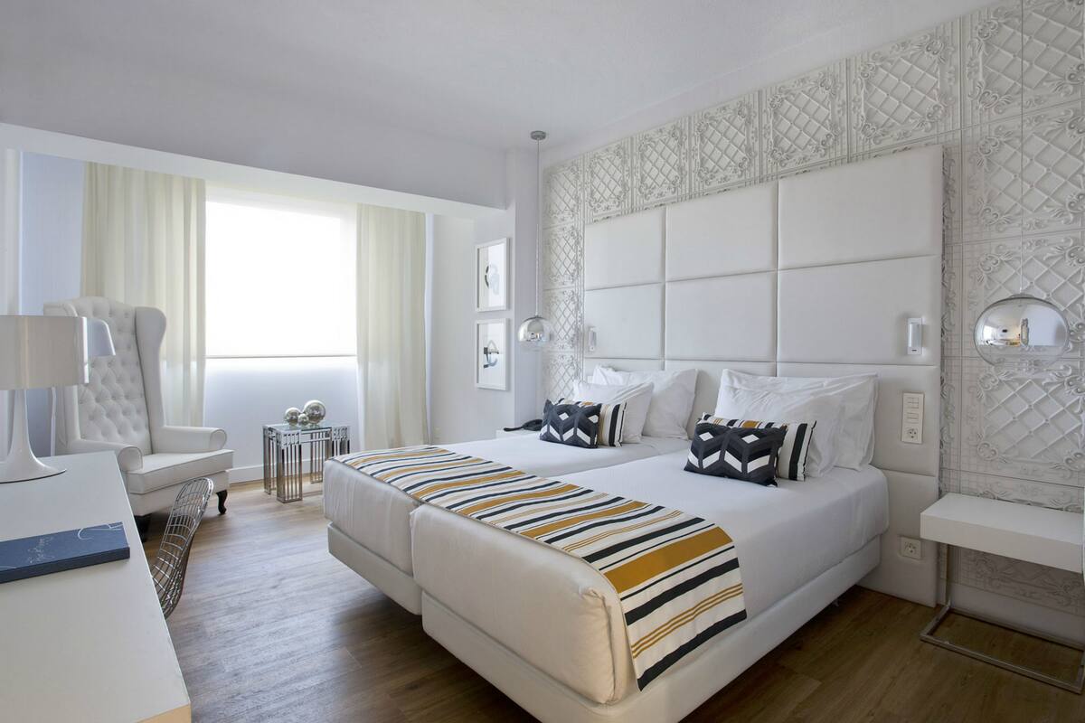 Quarto de hotel moderno com uma cama grande, uma escrivaninha e uma cadeira.