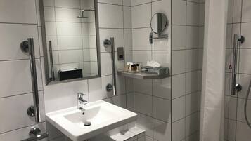 Uma casa de banho moderna com uma pia branca, um espelho, chuveiro e um porta-toalhas.