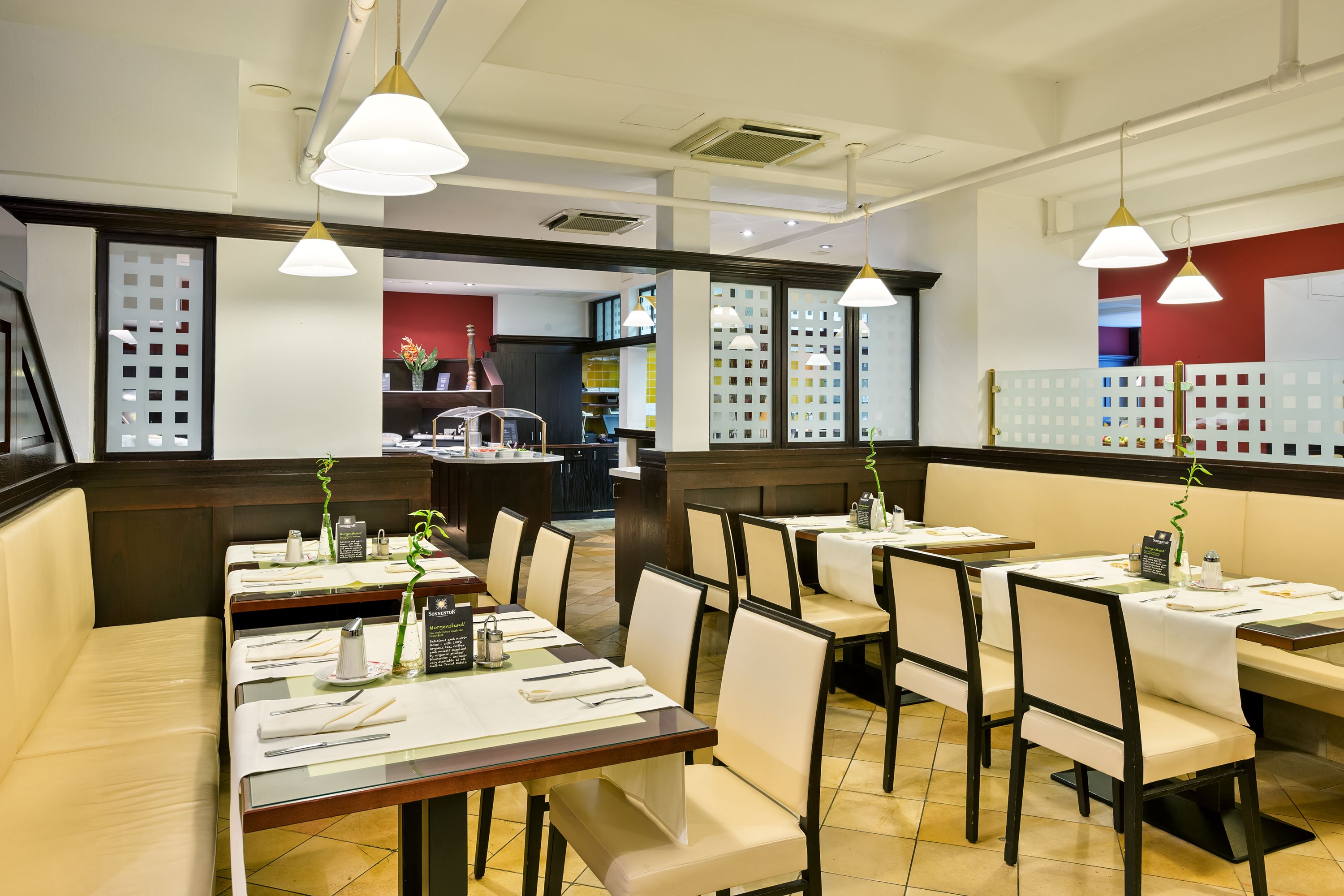 Um restaurante com mesas montadas para refeições, cadeiras e luminárias pendentes.
