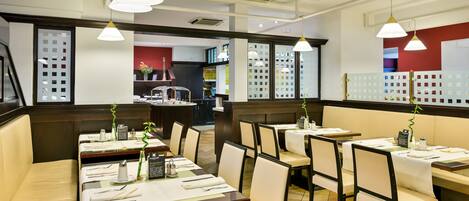 Um restaurante com mesas montadas para refeições, cadeiras e luminárias pendentes.