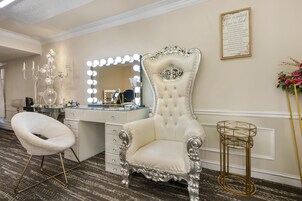 Uma área de toucador luxuosa, com um espelho grande, uma cadeira decorada e um móvel com gavetas.