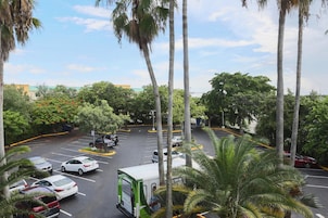 Um estacionamento com vários carros e um ônibus de transporte verde e branco.