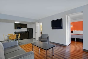 Apartamento moderno com área de refeições, cozinha compacta, sala de estar e um quarto com parede de destaque laranja.