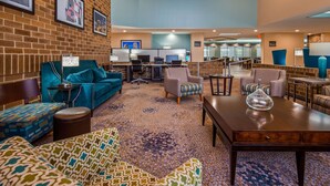 Um hall de hotel com parede de tijolos, área de estar e balcão de recepção.