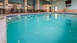 Piscina interna com água cristalina, espreguiçadeiras e posto de salva-vidas.