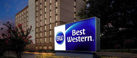 Placa de hotel com 'BW Best Western' e um edifício moderno ao fundo.