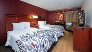 Quarto de hotel com duas camas, uma escrivaninha, uma televisão e uma cadeira.
