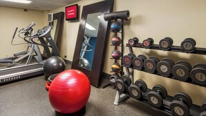 Uma academia com equipamentos de ginástica, incluindo esteira, bolas de exercício e halteres.