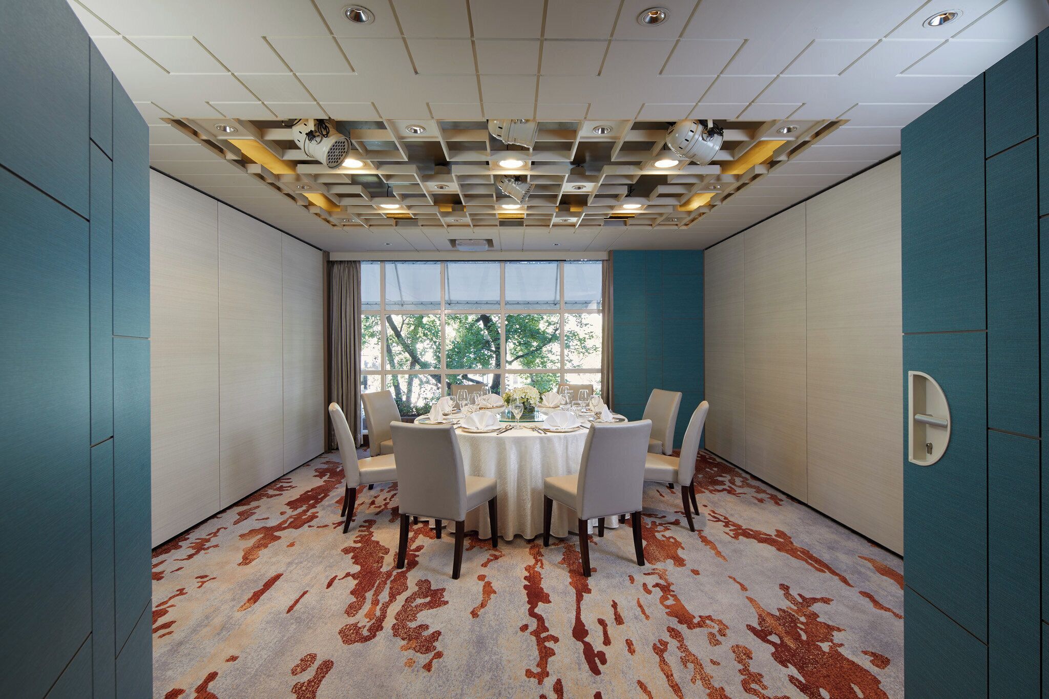 Uma sala de conferências com uma mesa redonda, cadeiras e piso coberto de carpete.
