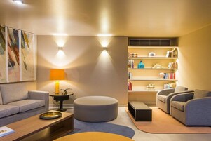 Uma sala de estar moderna com sofá, apoio para os pés e estante.