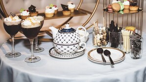 Uma mesa de sobremesas com diversos doces, cupcakes e um conjunto de chá.