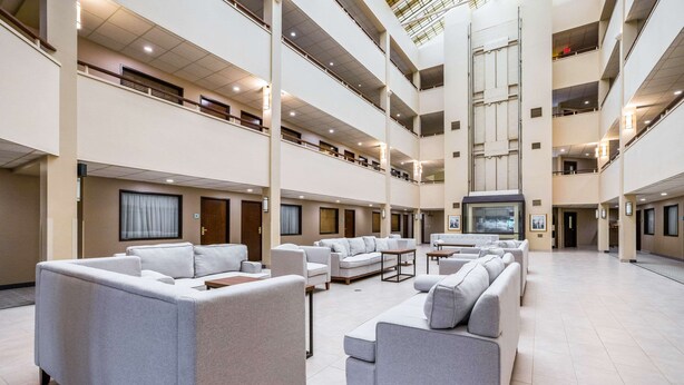 Um hall amplo em vários níveis, com mobiliário moderno e uma tela grande.