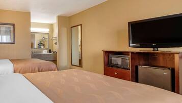Quarto de hotel com duas camas, televisão, micro-ondas e frigorífico.