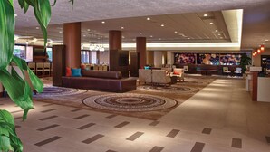 Um hall amplo com área de estar central, balcão de recepção e um grande painel decorativo.