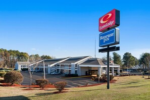 Um motel com uma placa para EconoLodge e Rodeway Inn, com estacionamento e um edifício com galeria coberta.