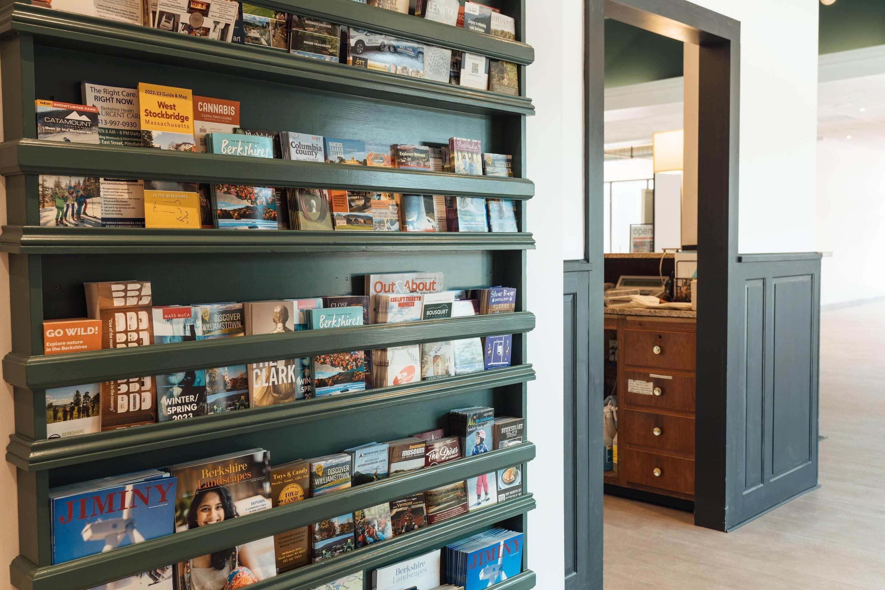Uma estante com diversos livros e folhetos, incluindo títulos como 'JIMINY' e 'Paisagens do Berkshire'.