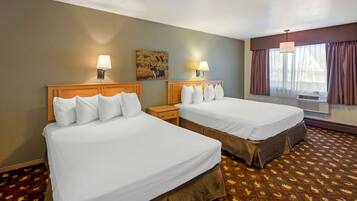 Quarto de hotel com duas camas, uma janela grande com cortinas, aparelho de ar condicionado e um quadro pendurado na parede.