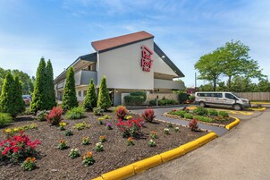 Um Red Roof Inn com design moderno, jardim ajardinado e área de estacionamento.