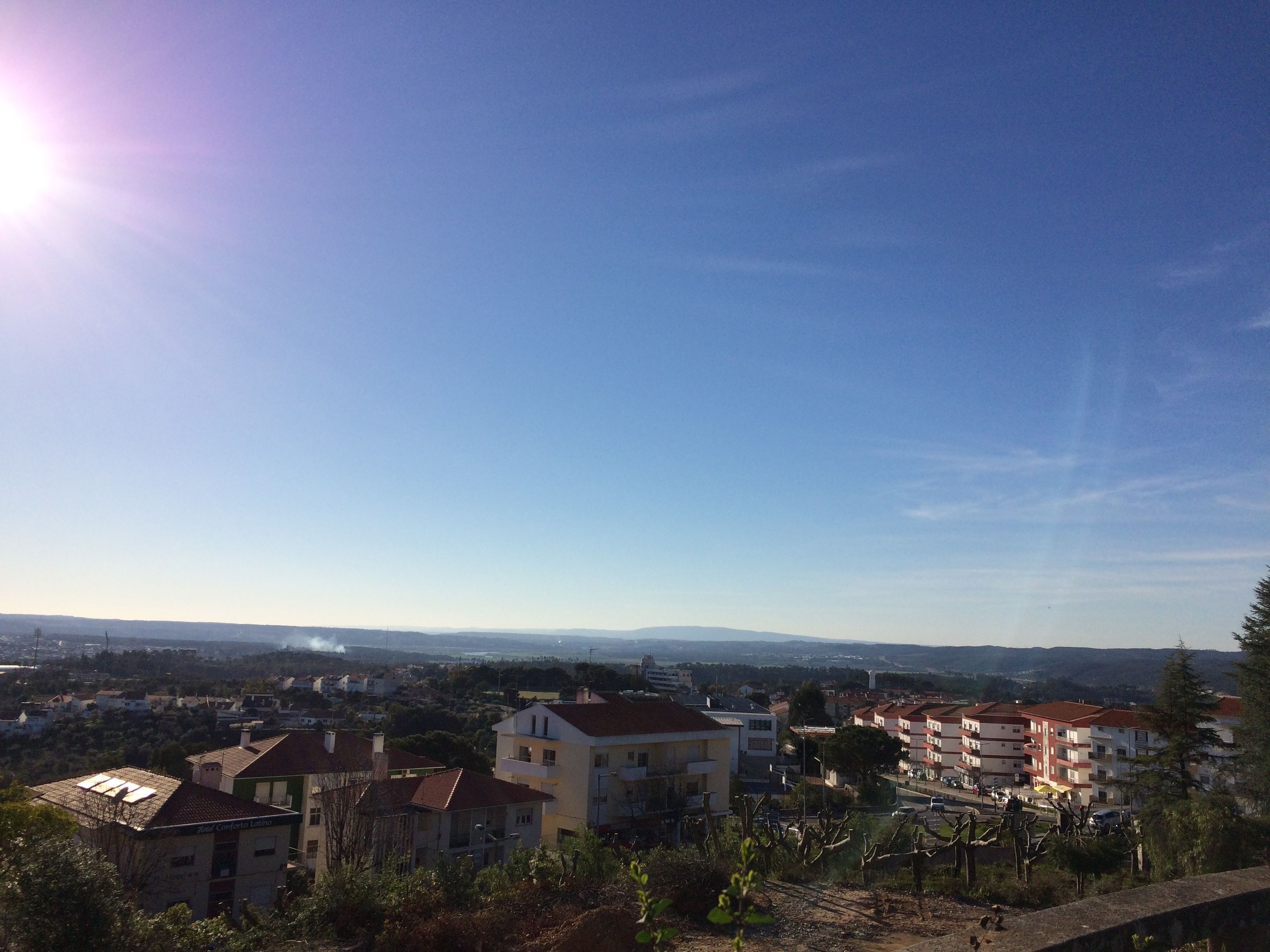 Zona residencial com edifícios, céu claro e vista distante de montanhas.