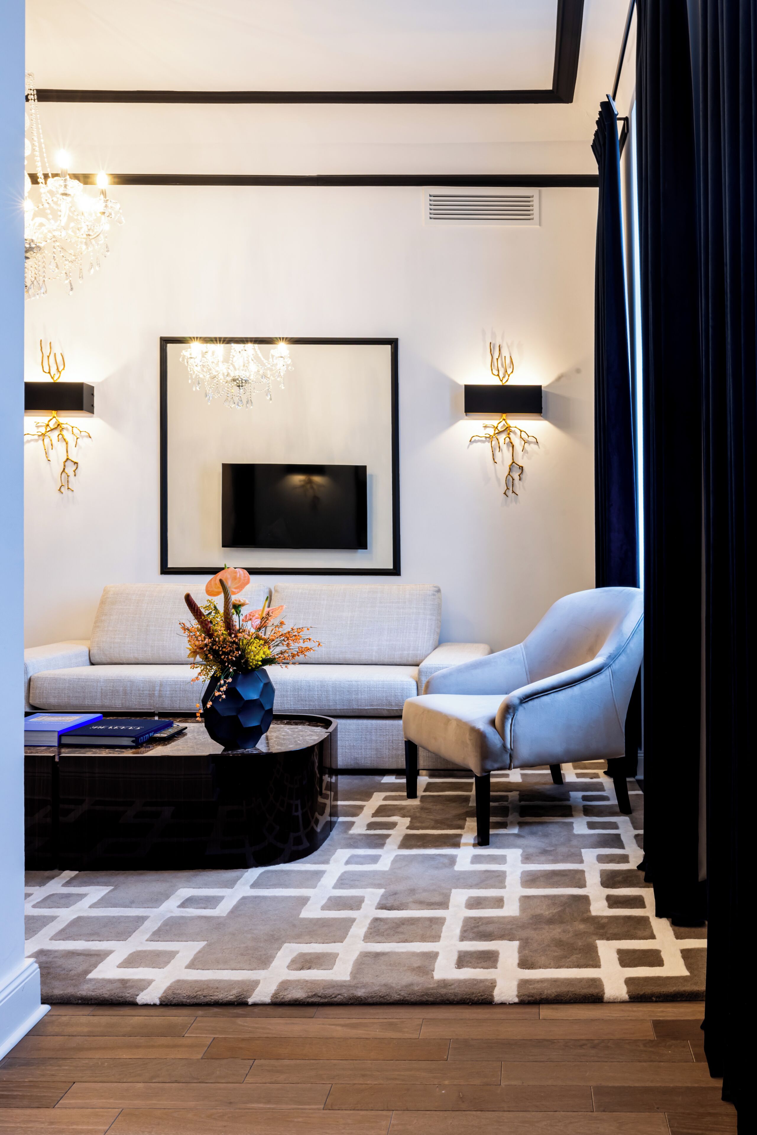 Uma sala de estar moderna com sofá, poltrona, mesa de centro e um vaso decorativo.