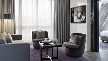Quarto de hotel moderno com sofá, poltrona e uma mesinha com objetos decorativos.