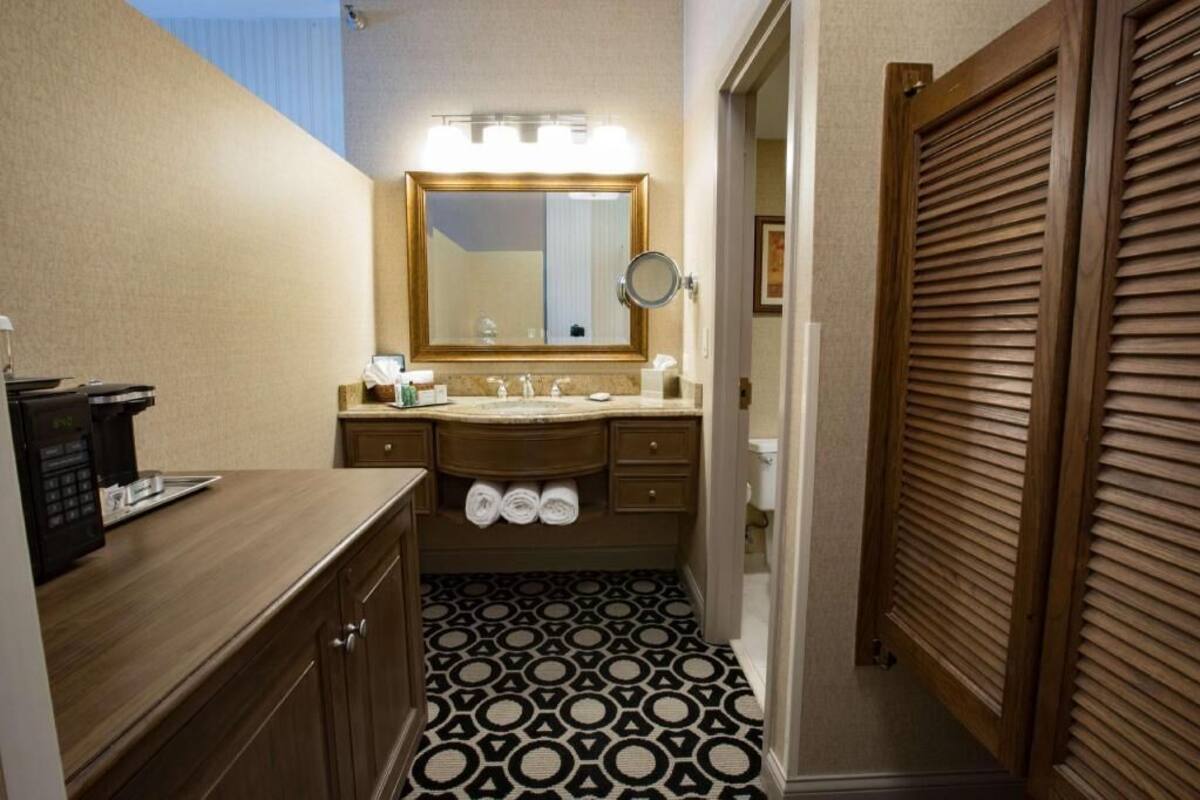 Casa de banho com lavatório, espelho, porta-toalhas e máquina de café.