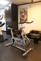 Uma academia com bicicletas ergométricas, uma garrafa de água e um cartaz da Mona Lisa.