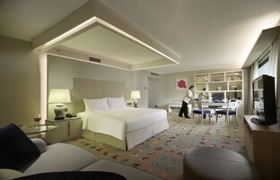 Quarto de hotel com uma cama, uma mesa, televisão e área de estar.