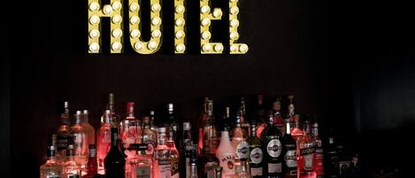 Uma área de bar com um letreiro de neon que diz "PENT HOTEL" e diversas garrafas de bebidas alcoólicas.
