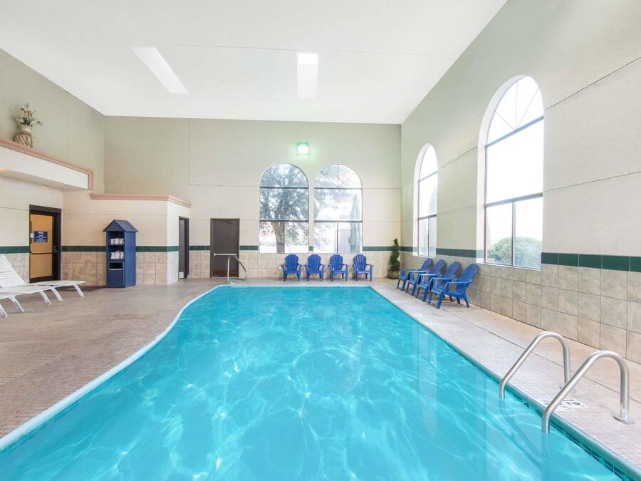 Piscina interior com água azul cristalina, cercada por espreguiçadeiras e piso ladrilhado.
