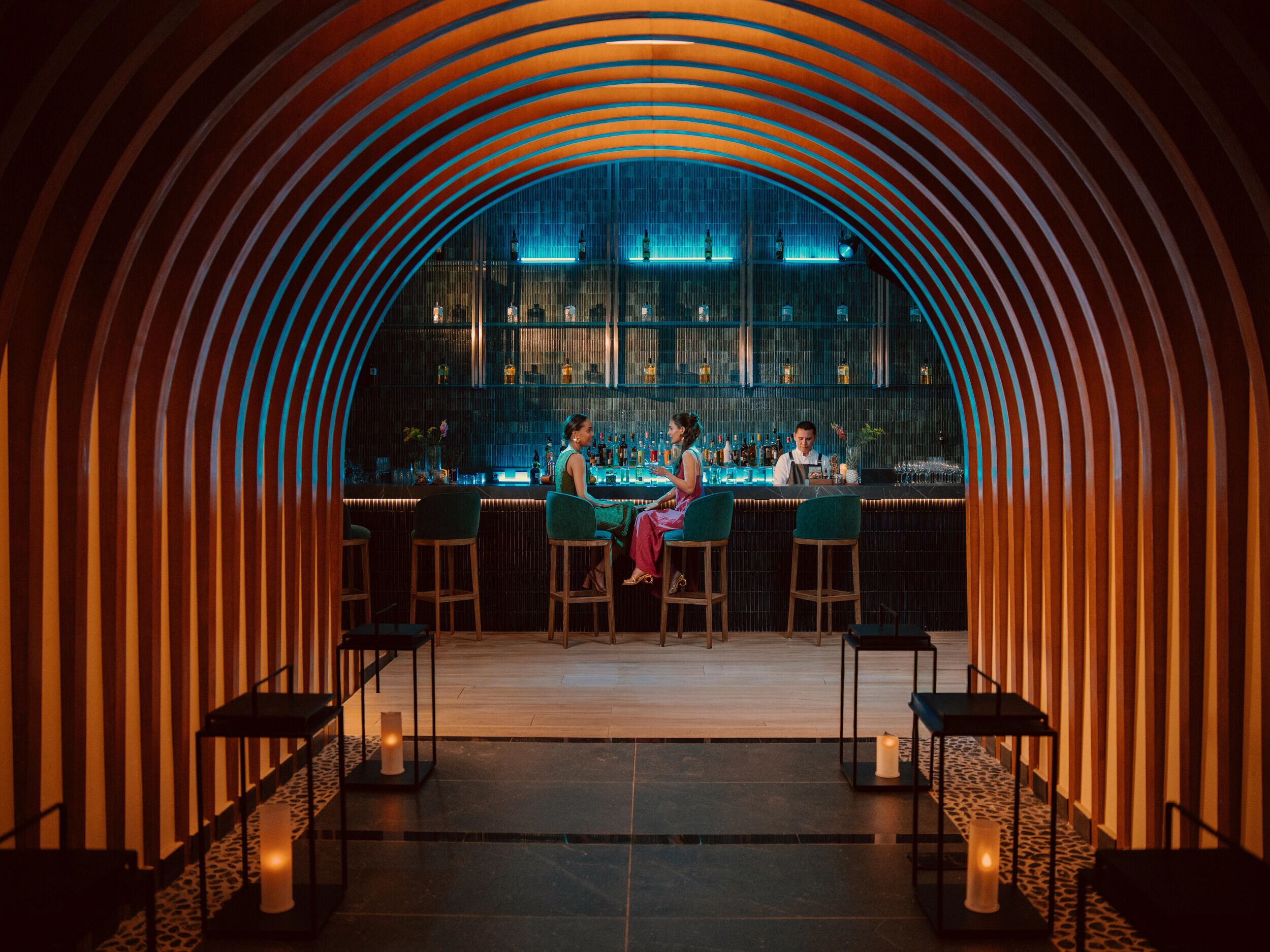 Um interior com área de bar, assentos e um chão estampado.