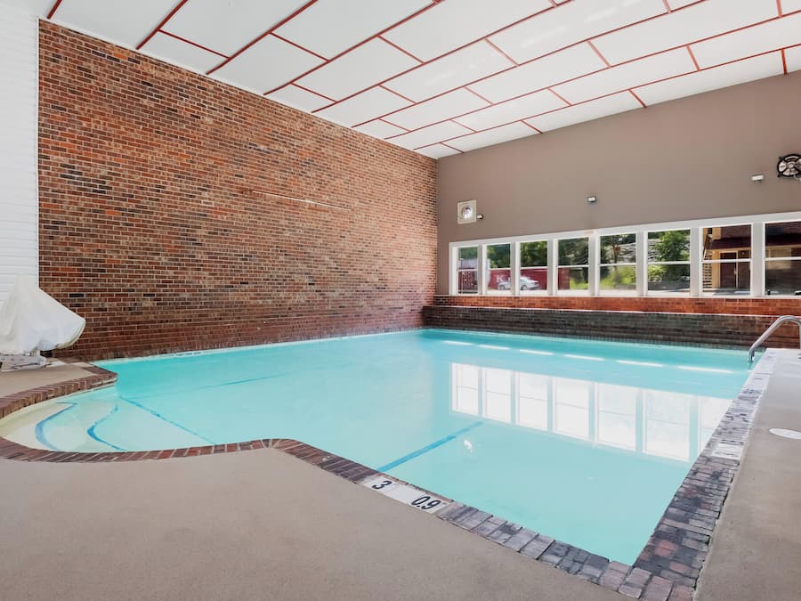 Piscina interior com parede de tijolos e amplas janelas.