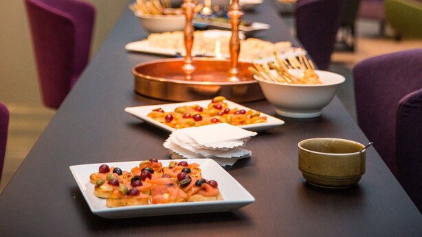 Mesa de jantar com diversos pratos, velas e luminária pendente.