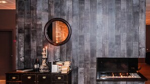 Quarto com parede de madeira, espelho redondo, lareira e cômoda preta com gavetas.