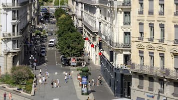 Uma rua larga com edifícios em ambos os lados, uma passarela para pedestres e um corpo d'água ao primeiro plano.
