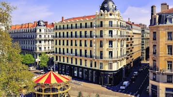Um edifício histórico com uma entrada de esquina imponente, um carrossel e vista livre para a rua.