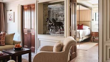 Quarto de hotel com sofá, poltrona e cama com travesseiro vermelho.