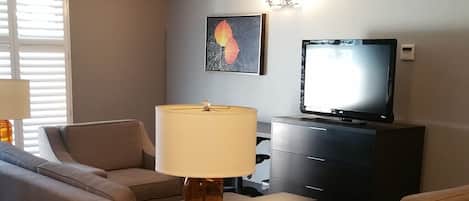 Uma sala de estar com sofá, mesa de centro, luminária, televisão e lareira.