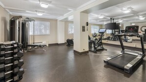 Uma academia com equipamentos de ginástica, incluindo halteres, esteira e bicicleta ergométrica.