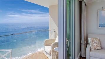 Varanda com vista para o oceano, mobiliário de vime e porta de vidro.