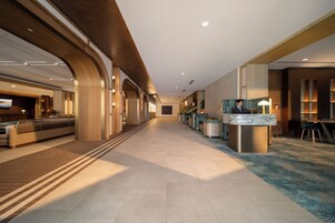 Um hall de hotel com balcão de recepção, área de estar e escadaria.