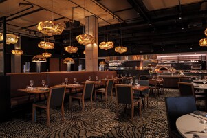 Interior de restaurante com cabines, mesas e luminárias pendentes.