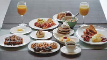 Uma mesa posta com diversos pratos e bebidas para o café da manhã.