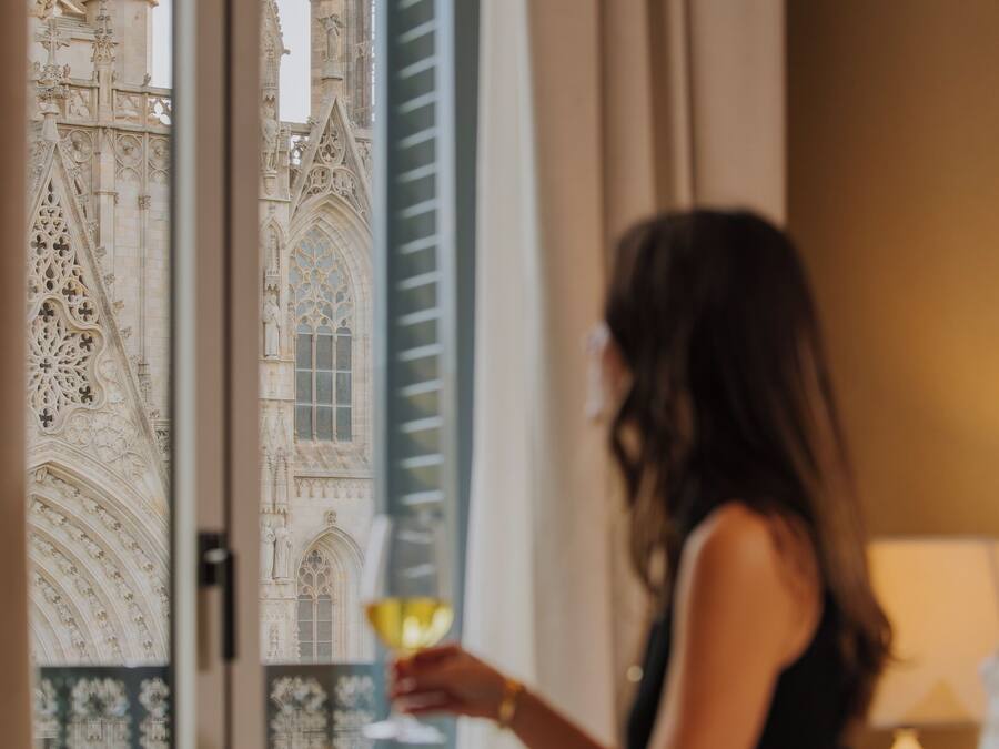 Quarto com uma grande janela com vista para um edifício histórico e arquitetura detalhada.