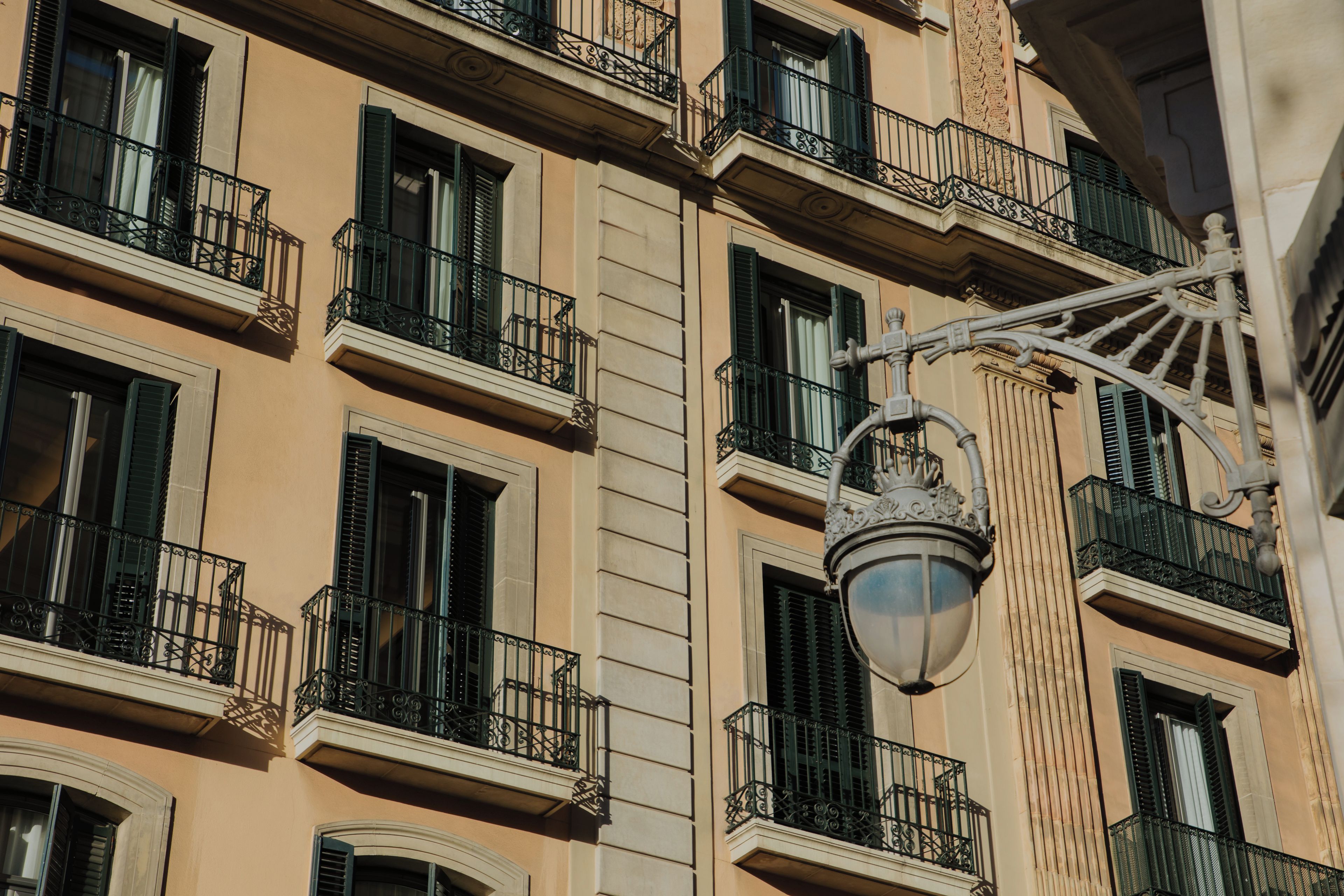 Um edifício de vários andares com sacadas, um poste de luz e uma janela com persianas.
