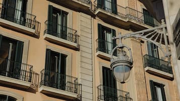 Um edifício de vários andares com sacadas, um poste de luz e uma janela com persianas.