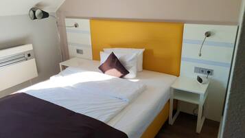 Quarto de hotel com cama, mesas de cabeceira, escrivaninha e luminária.